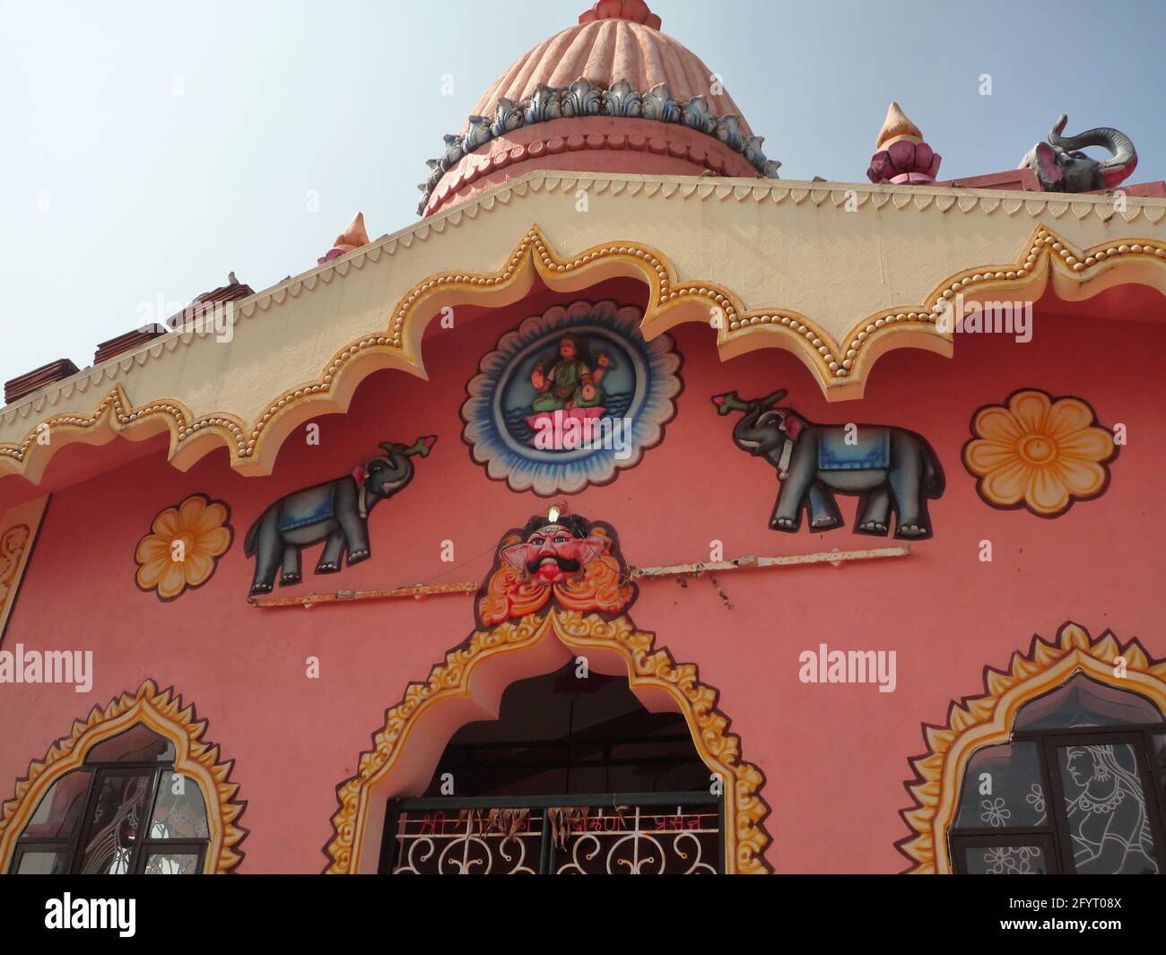 A pink Hinduistic building with colorful depictions of deities and ...