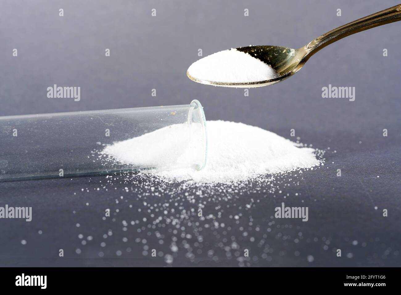 A metal spoon stuffing white powder into a capsule in a lab with ...