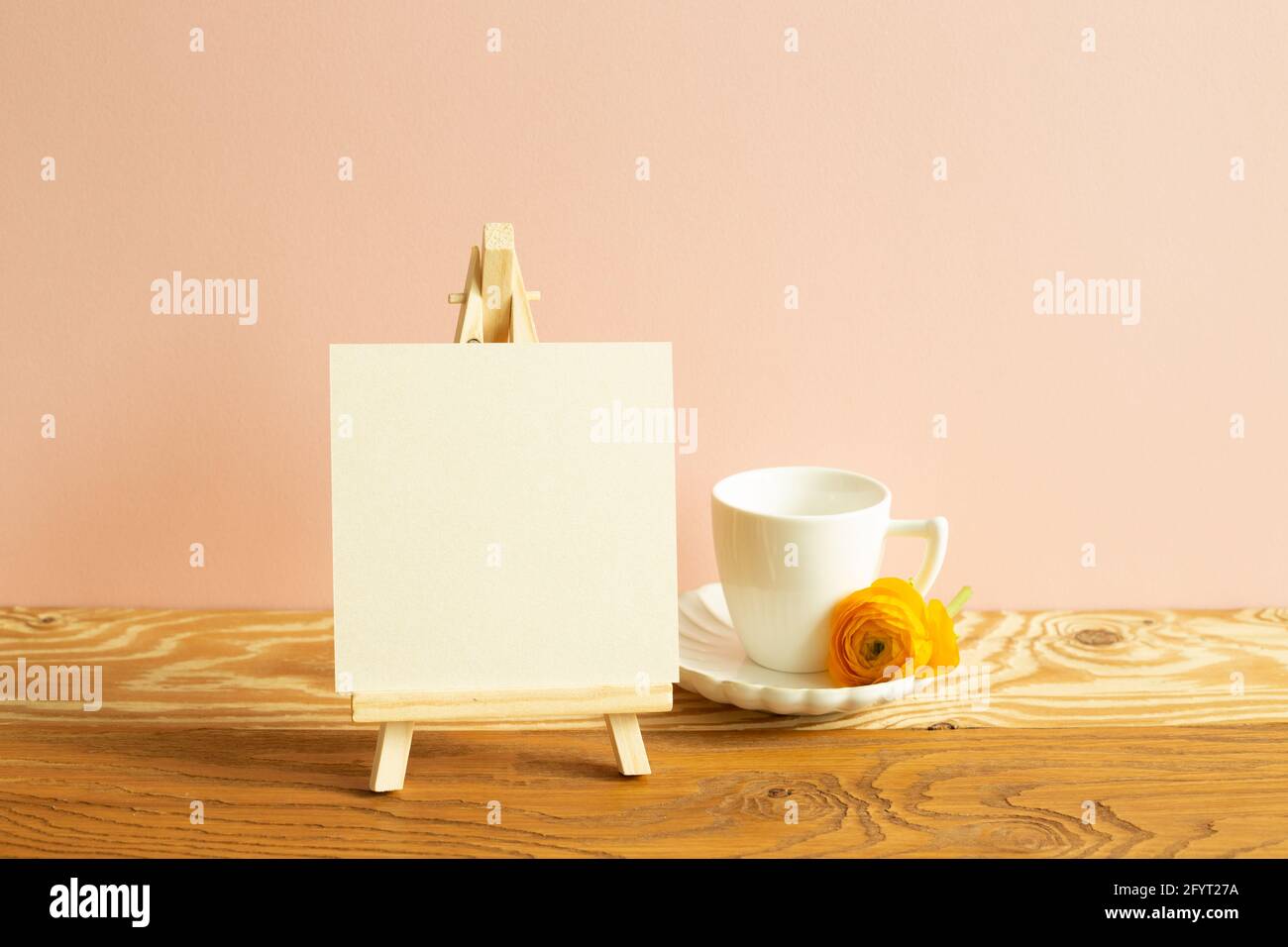 Easel and blank canvas with coffee cup on wooden table. pink background ...
