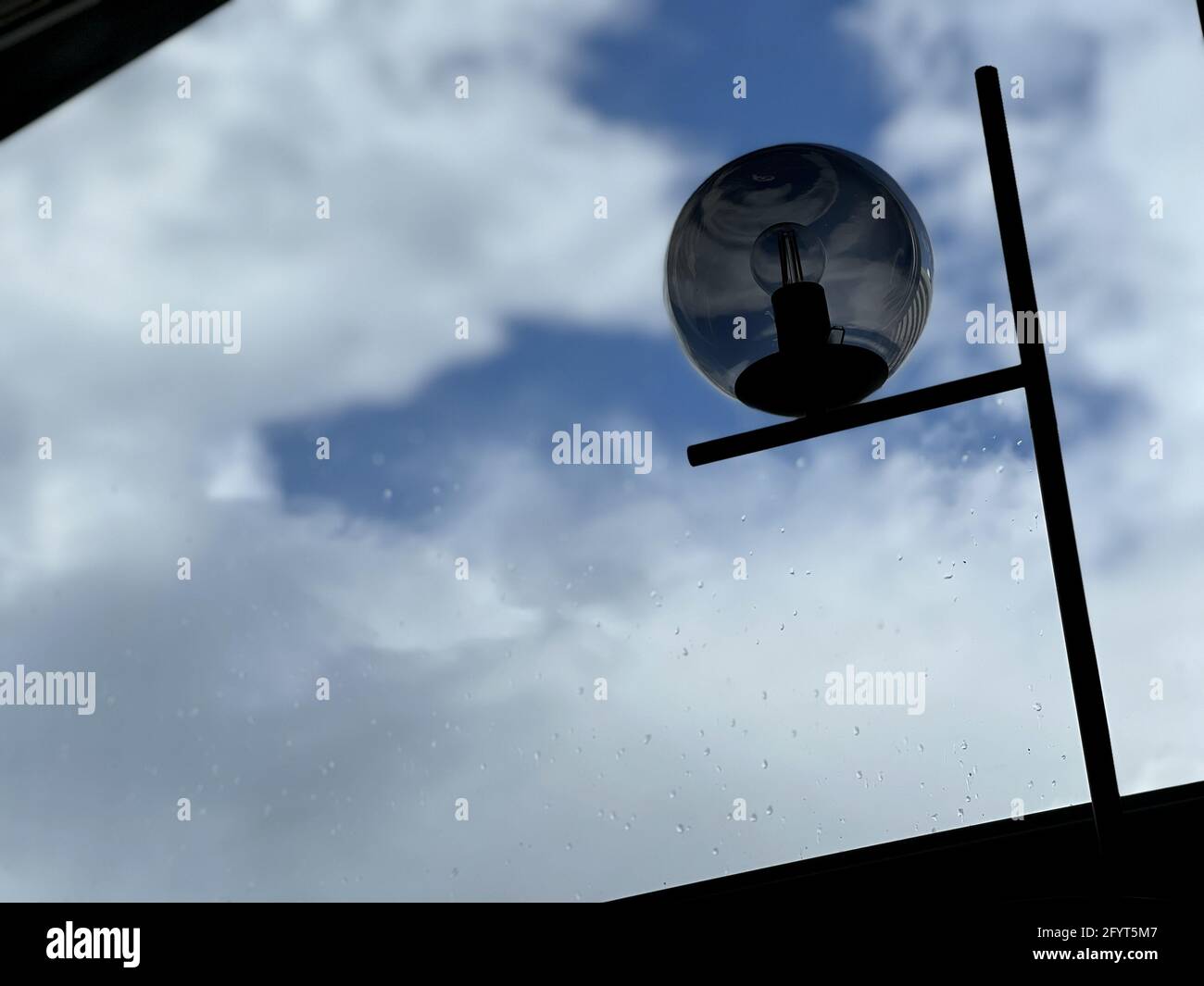 A modern street lamp post in the cloudy sky background; a view out of ...