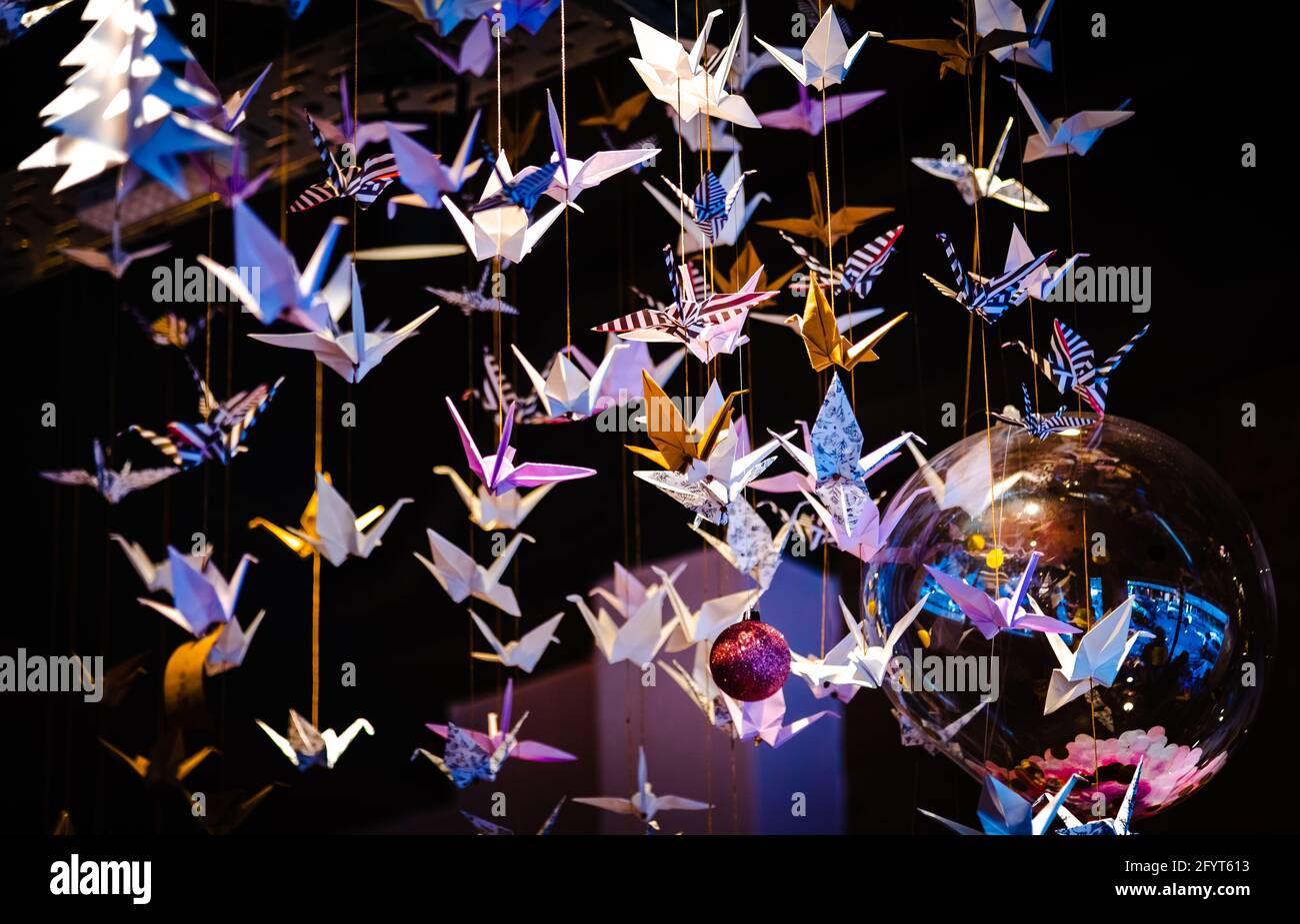 Lots of origami swans hanging from the roof, seen from underneath in a ...