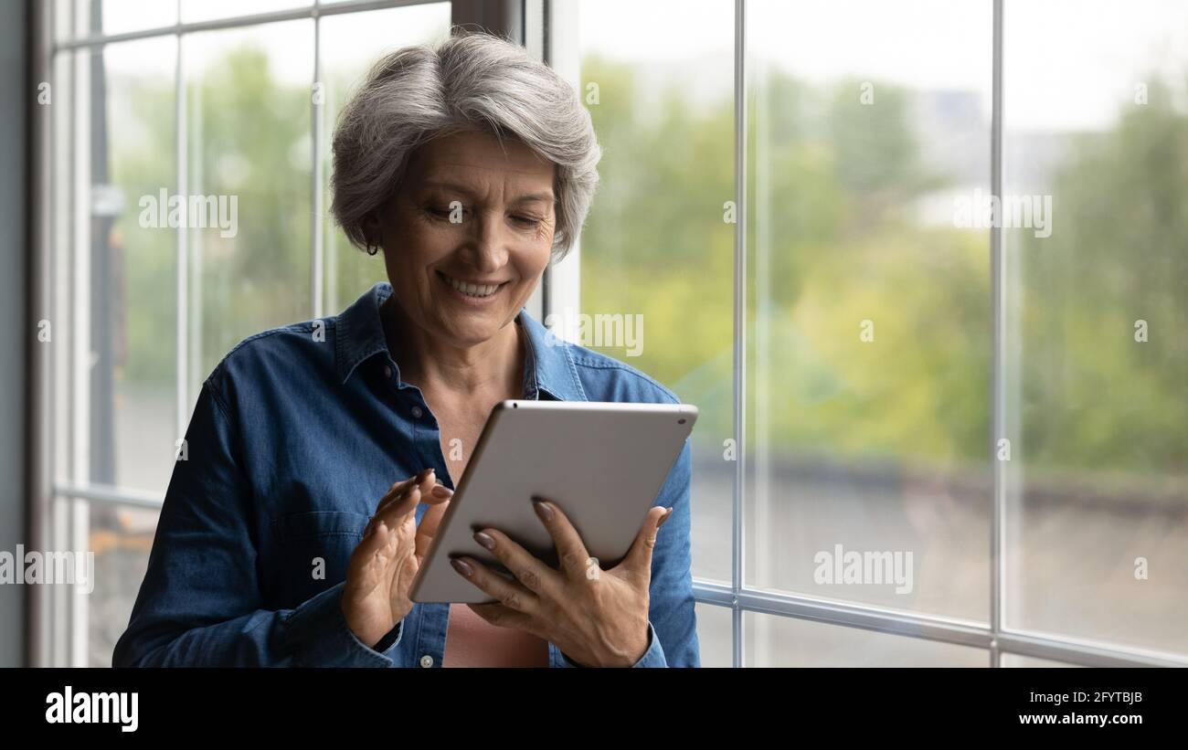 Happy mature woman holding tablet use online services Stock Photo - Alamy
