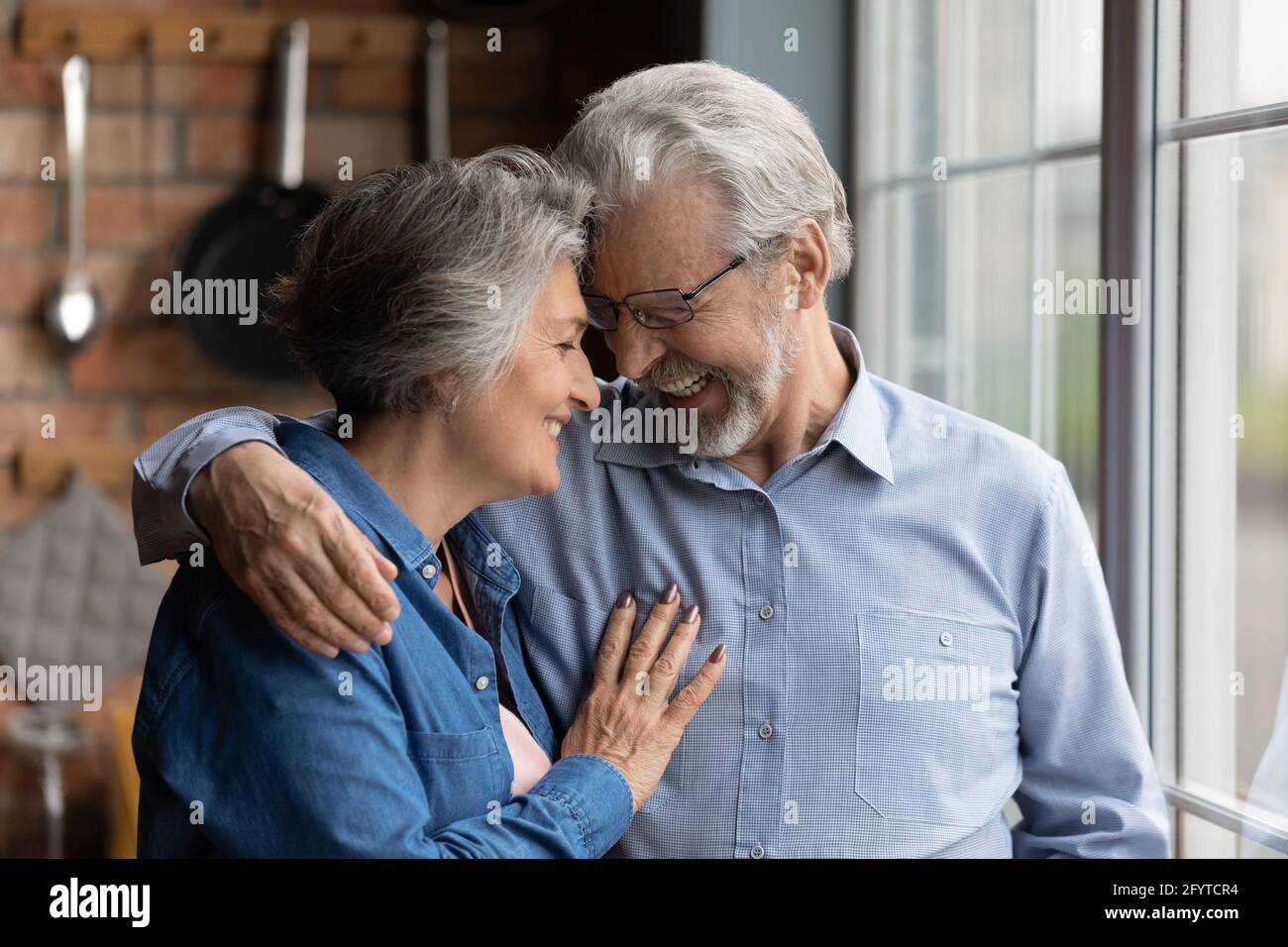 Cheerful mature couple in love hugging standing indoor Stock Photo - Alamy