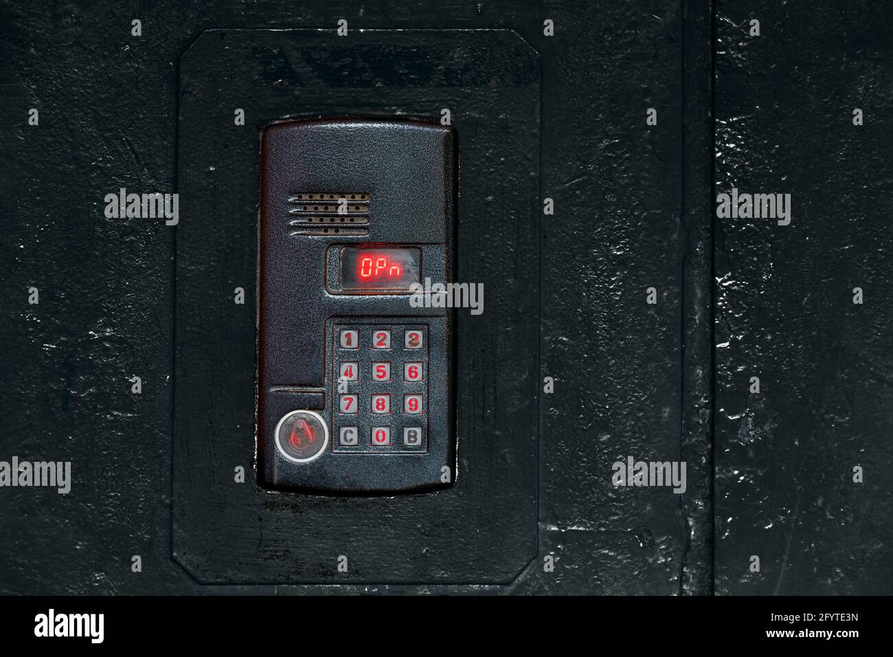 An intercom on old black painted steel surface with a keypad, digital ...