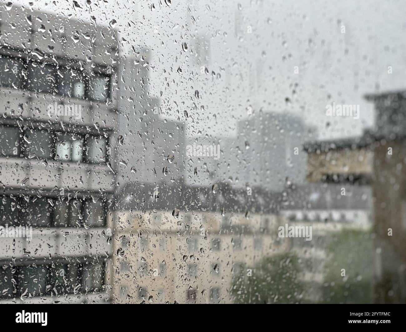 Many raindrops on the window glass with buildings on the background ...