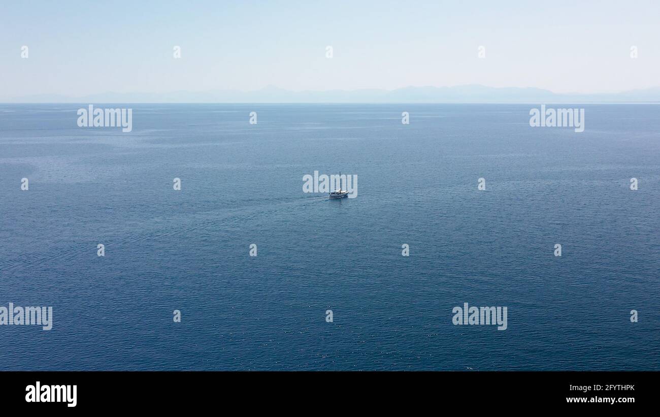Aerial shot in the open sea with a view of a white boat sailing in ...