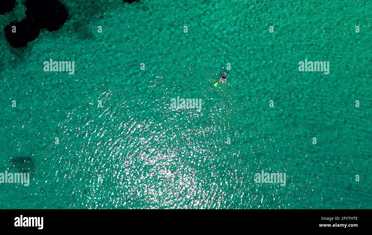Aerial view above diver, in the shallows, transparent waters of the ...