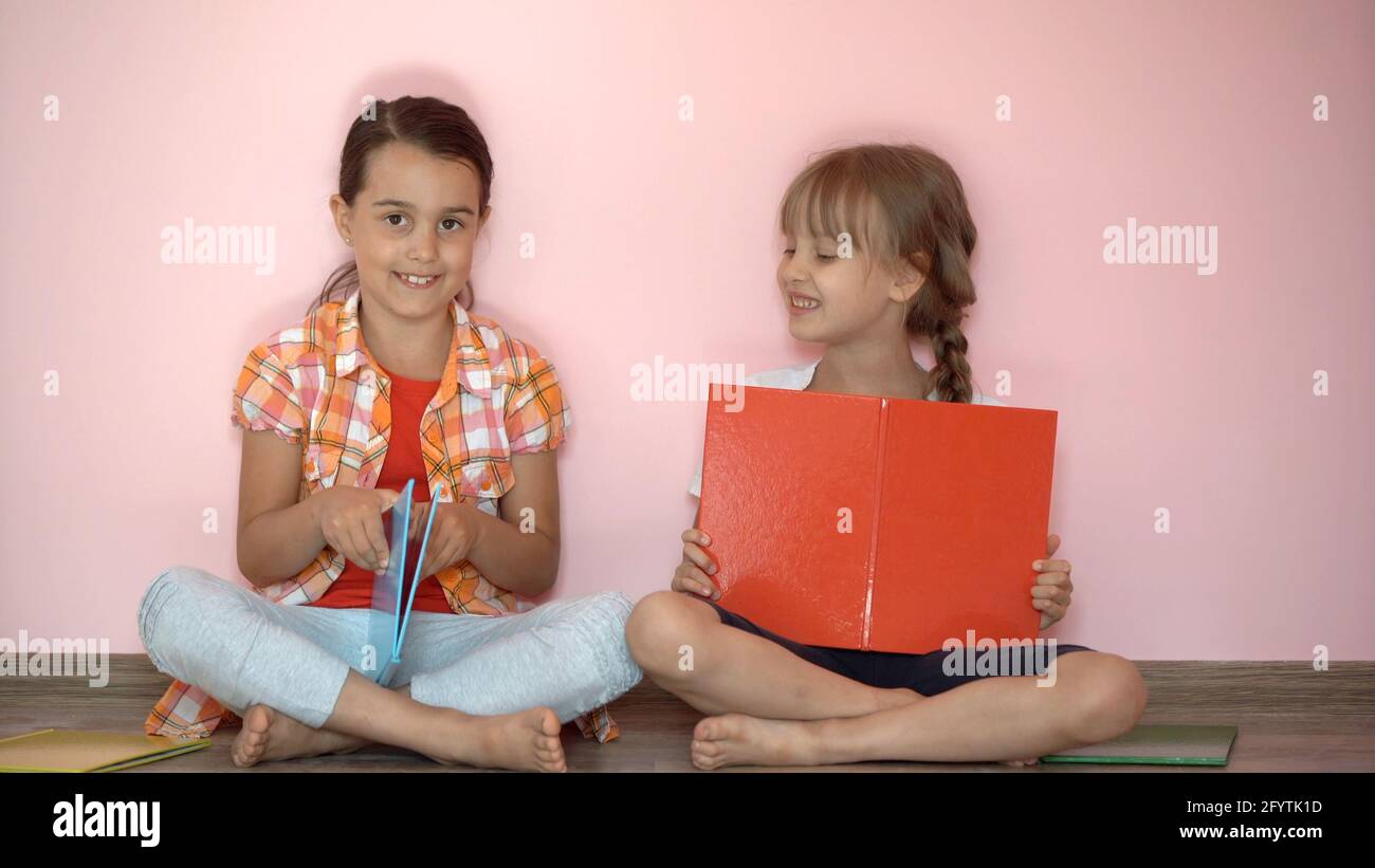 Lovely little girls are reading a book. The concept of education ...
