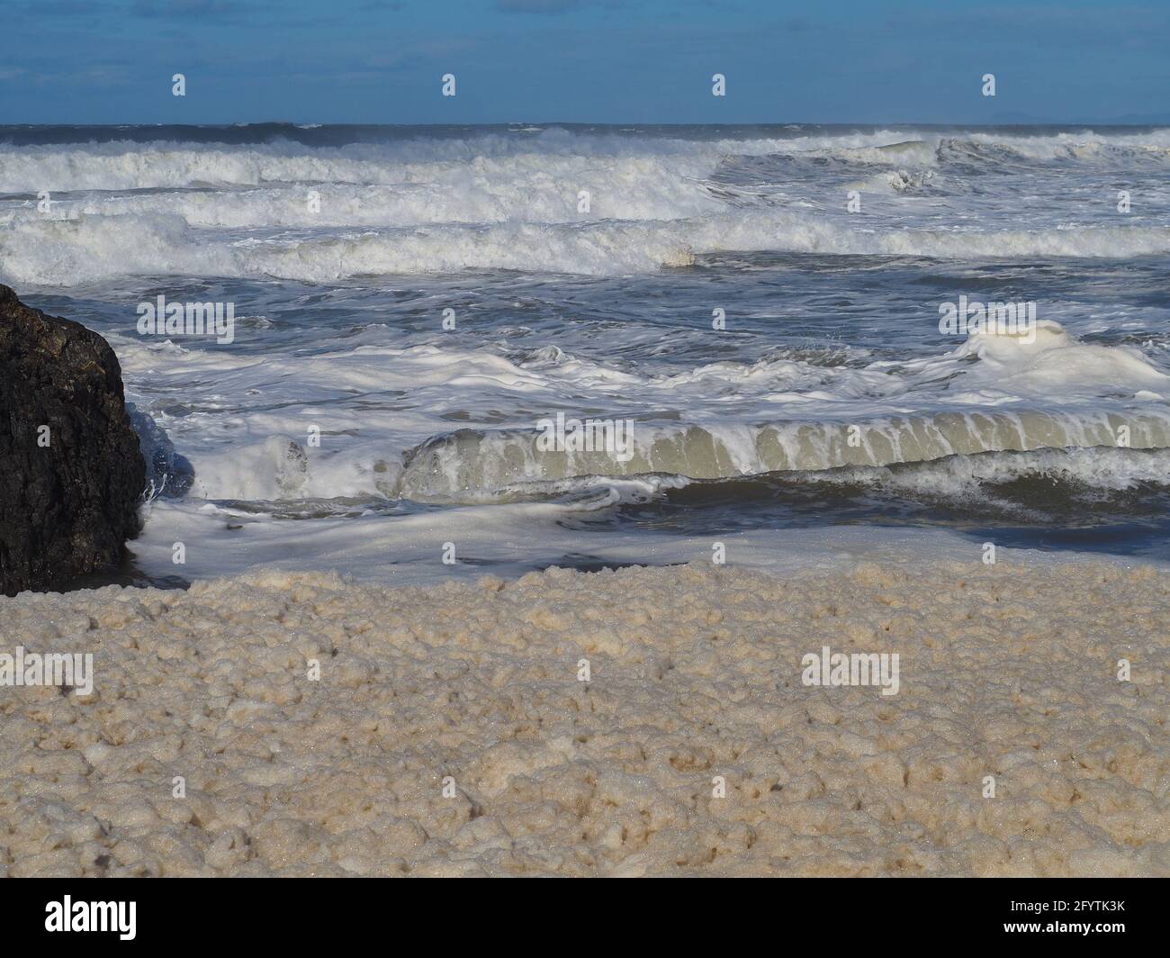 Dirty sea foam blown off the ocean waves crashing into a rock pool by ...