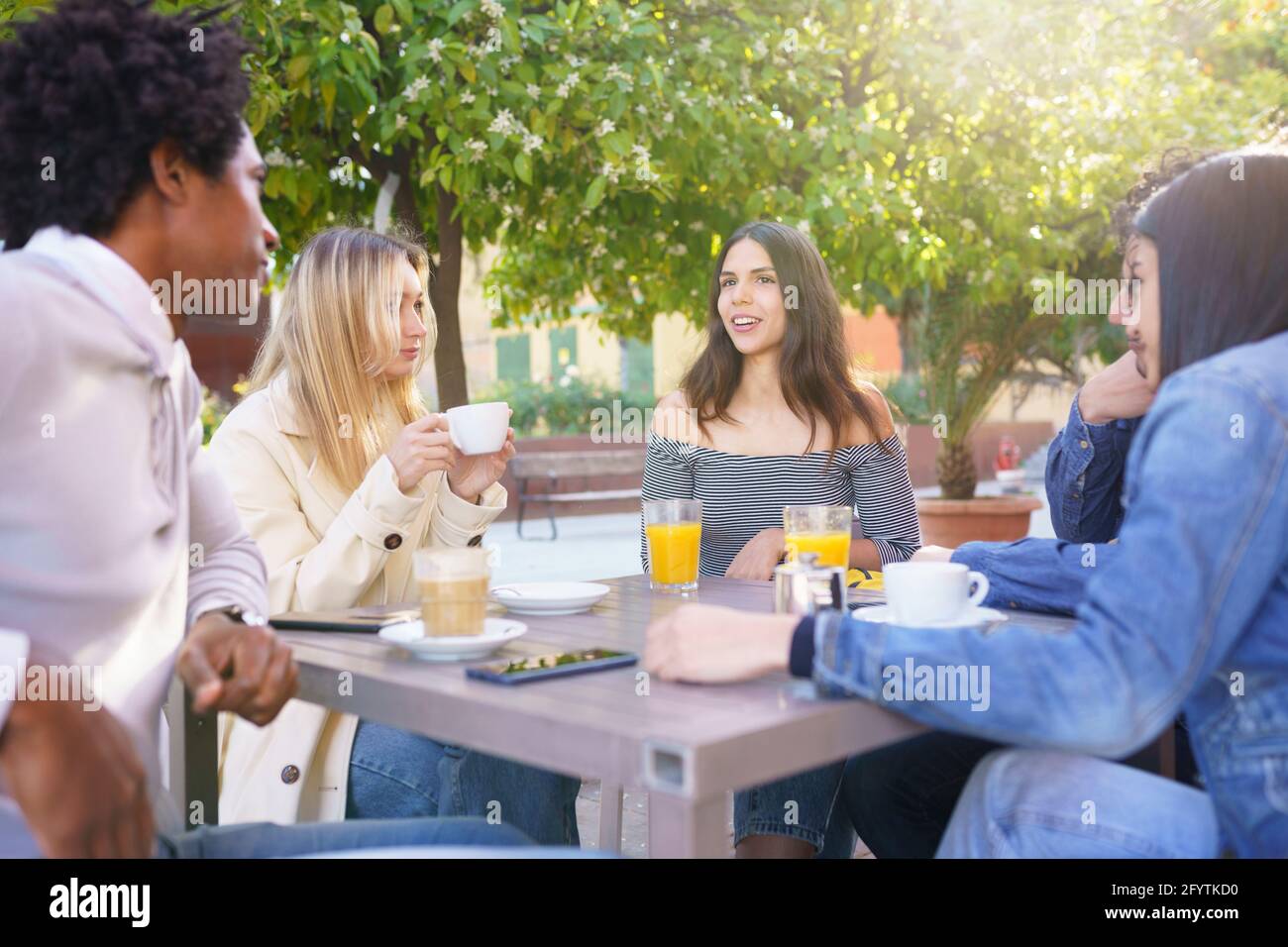 Multi-ethnic group of students having a drink on the terrace of a ...