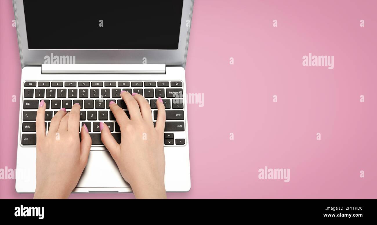 Top view image of perfect female hands typing on a laptop on a pink ...