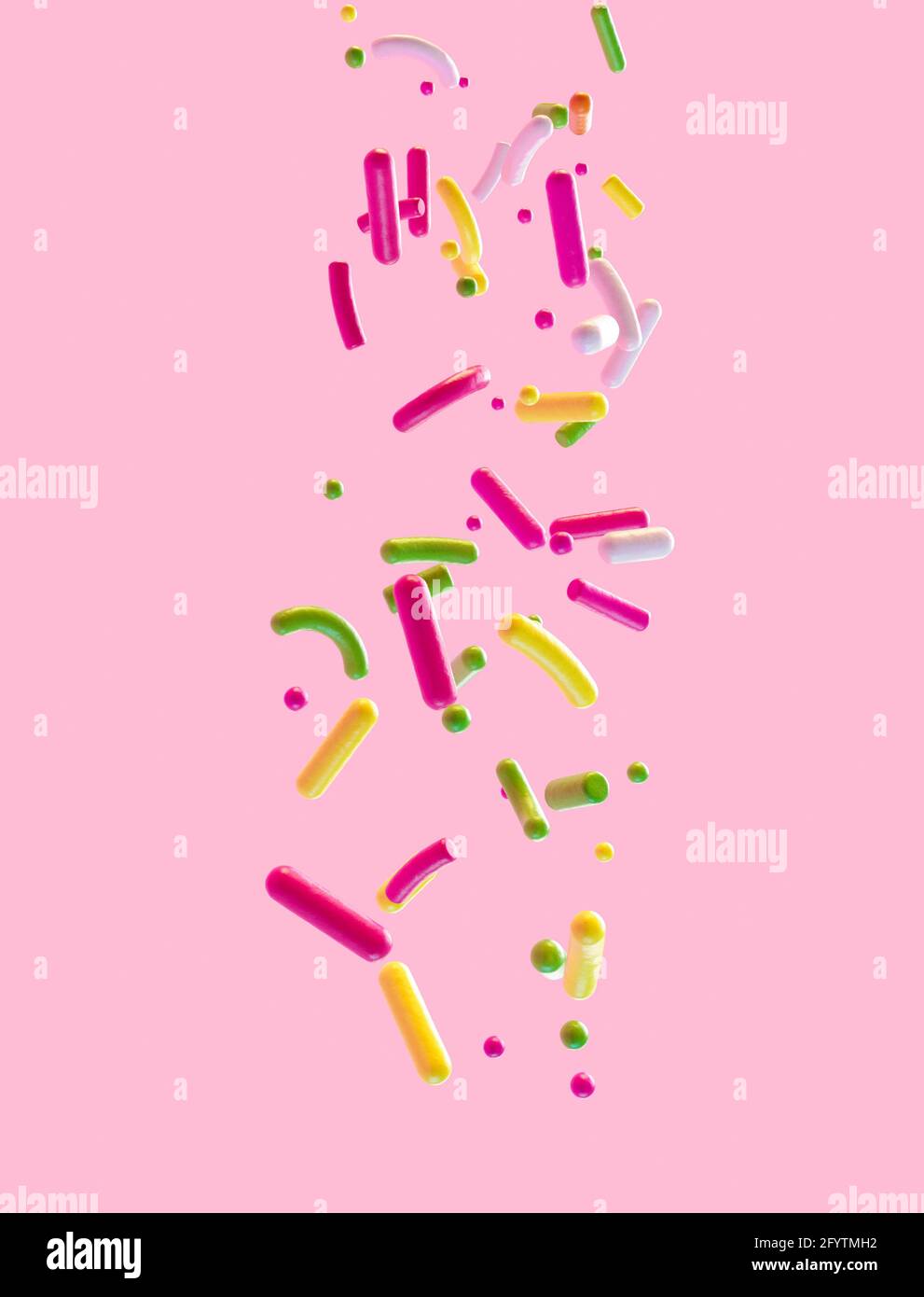 A vertical shot of falling Sprinkles isolated on a pink background ...