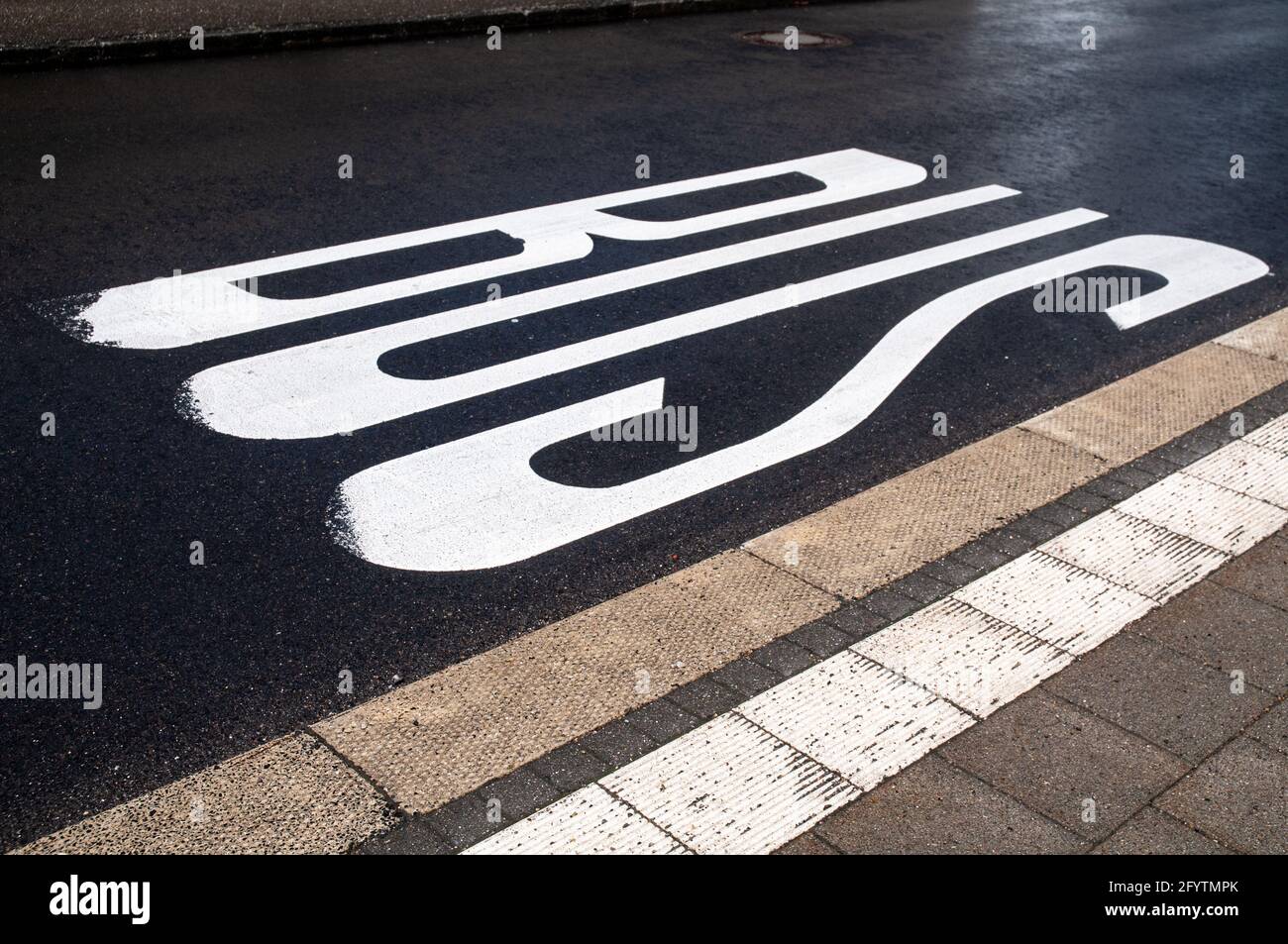 white text on a street next to a sidewalk marking a bus stop Stock ...