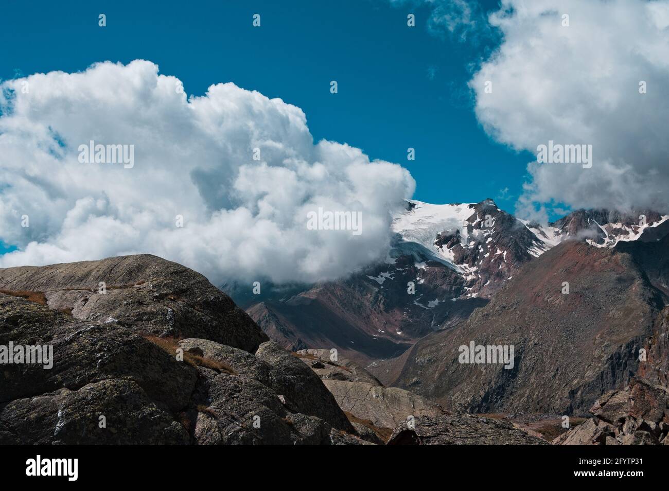 Big clouds above snow capped peaks of mountains in the italian Alps ...
