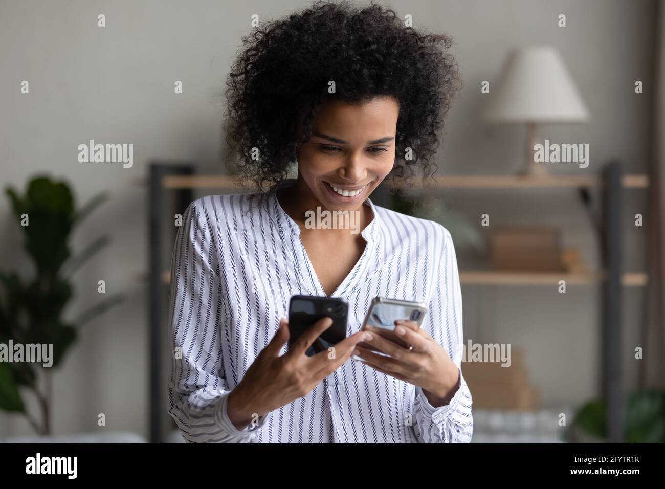 Happy African American woman use two modern smartphones Stock Photo - Alamy