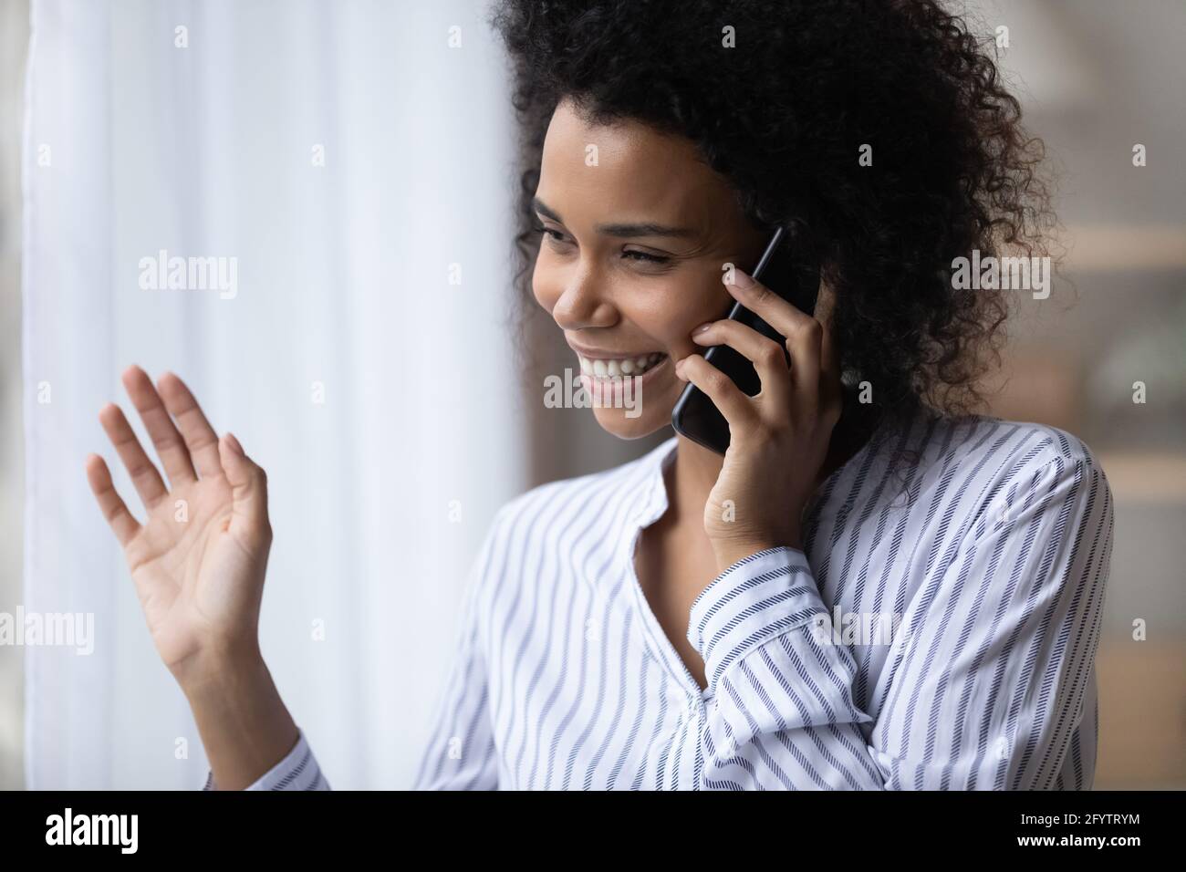 Happy biracial woman talk on smartphone look in window Stock Photo - Alamy