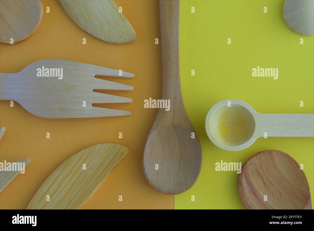 A top view of wooden spoons, ladle, fork, and scoop on a yellow and ...