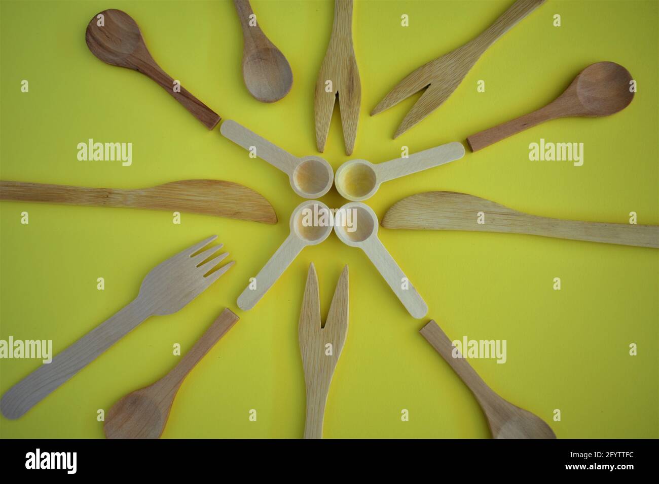 A top view of wooden spoons, ladle, fork, and scoops on a yellow ...