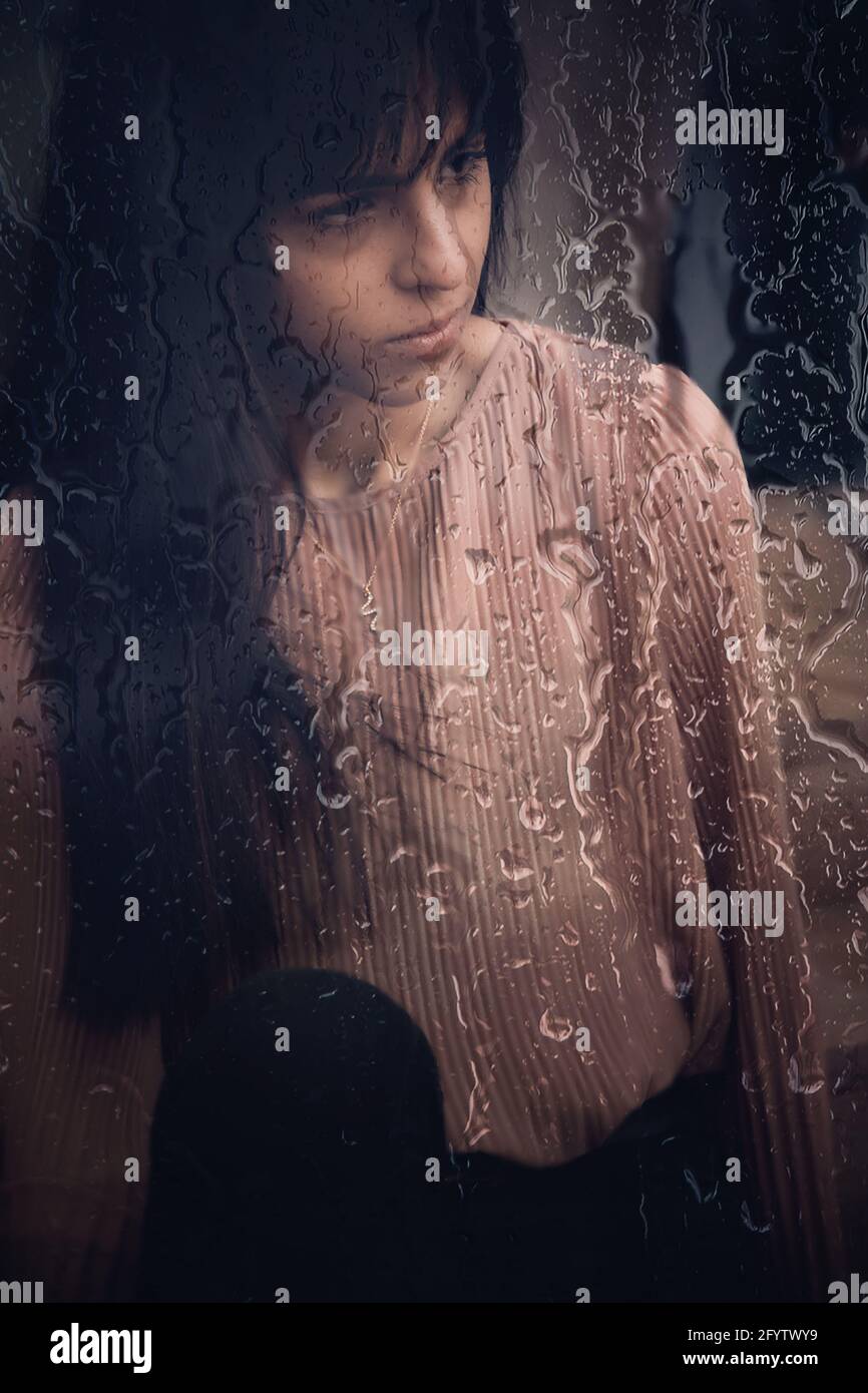 The beautiful brunette woman behind the window with raindrops Stock ...