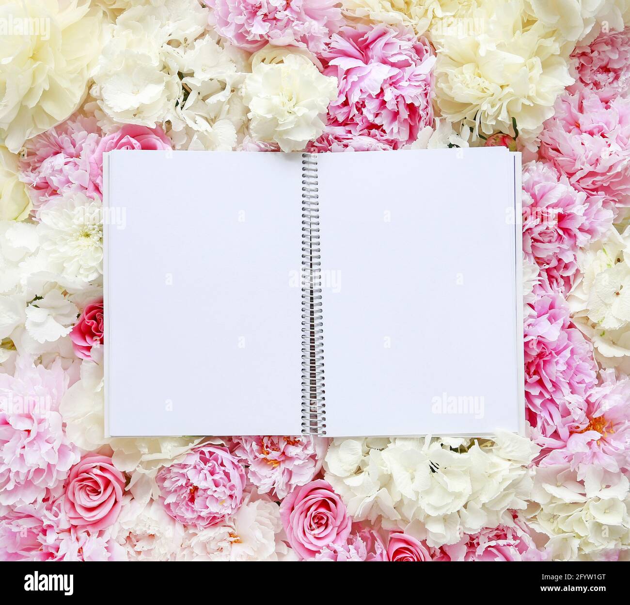 Open notebook with blank pages lying on flower background with peonies ...