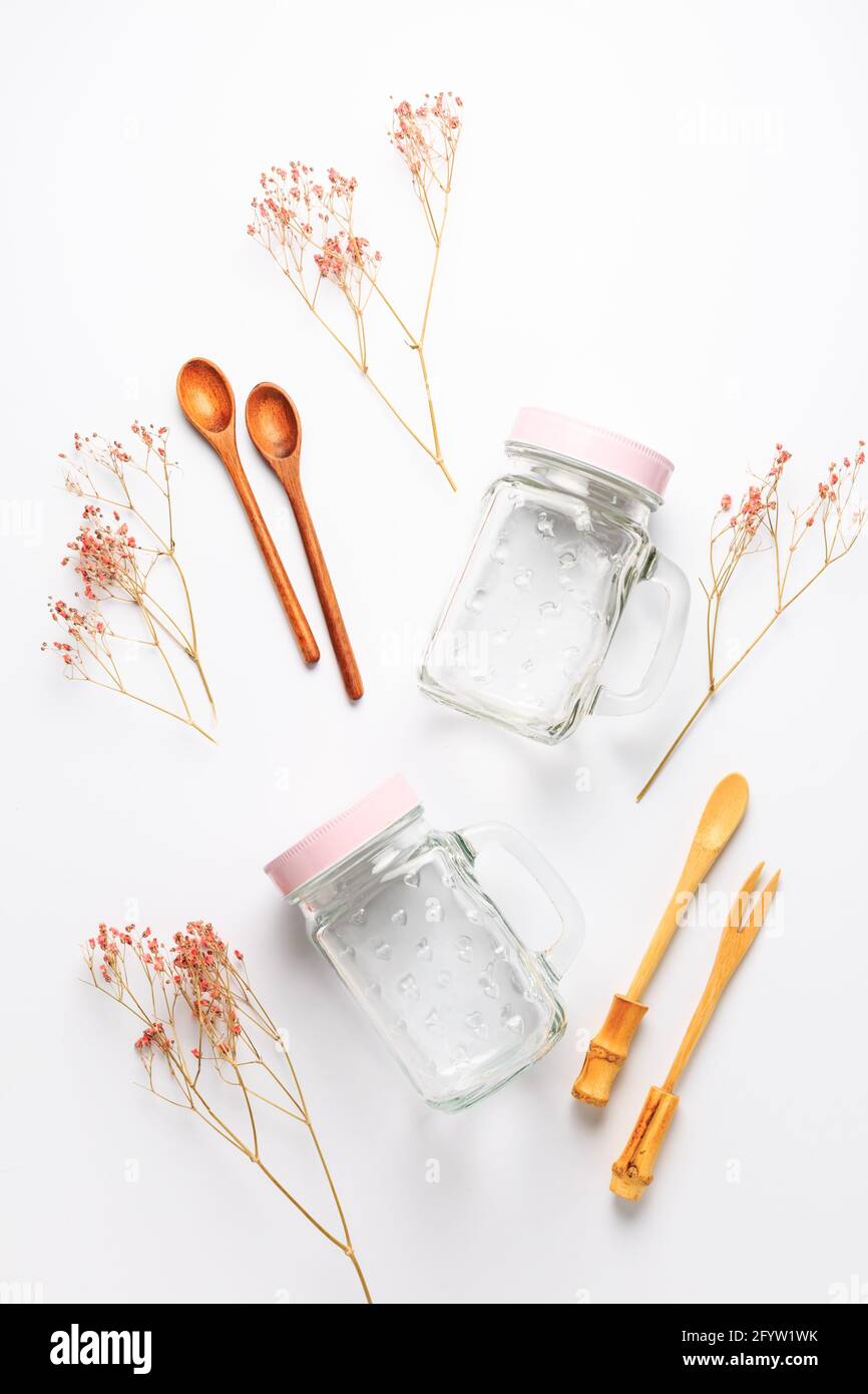 Empty drinking cups or jars with wooden spoons on white background ...