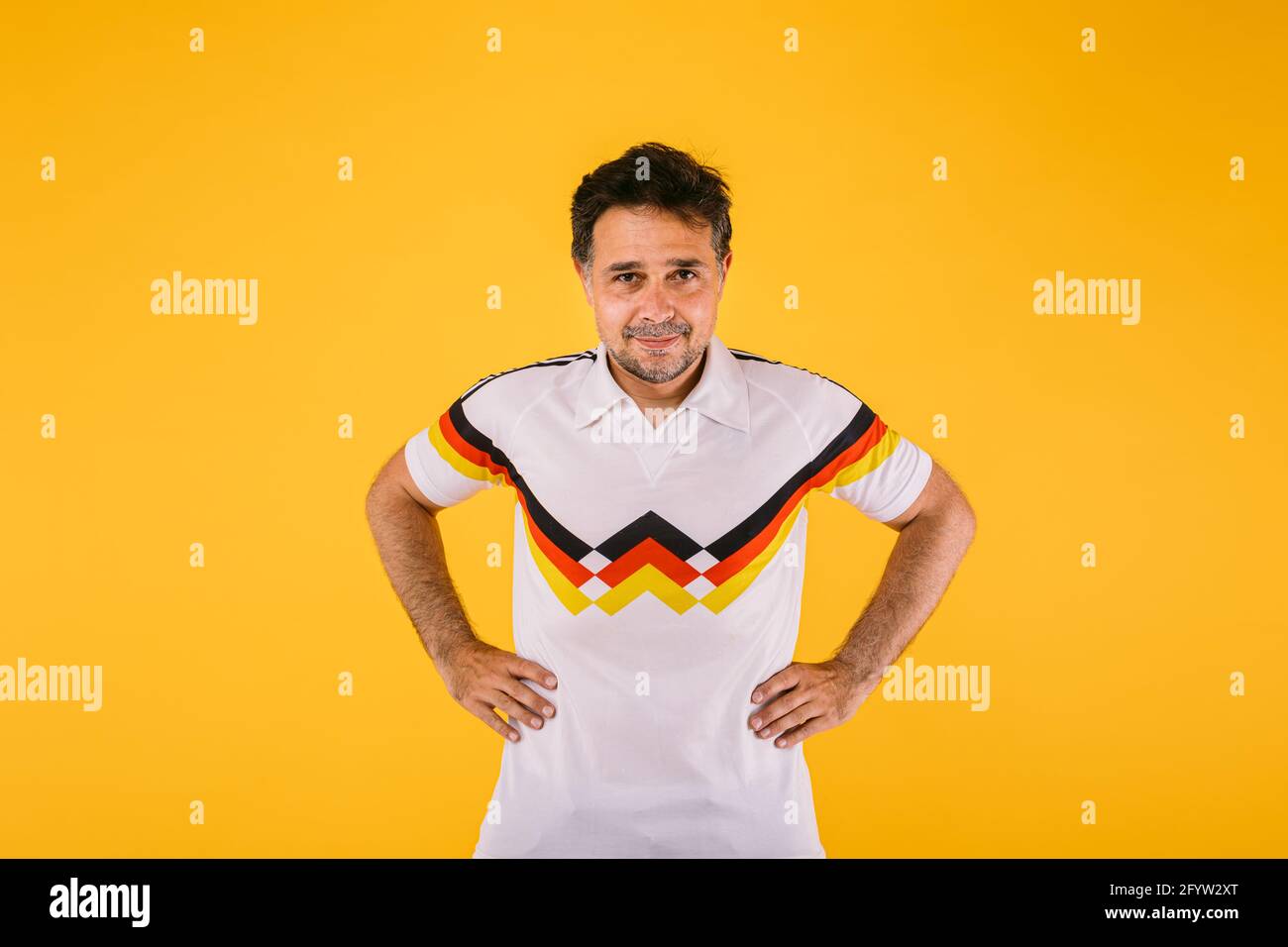 Soccer fan wearing a white t-shirt with black, red and yellow stripes ...