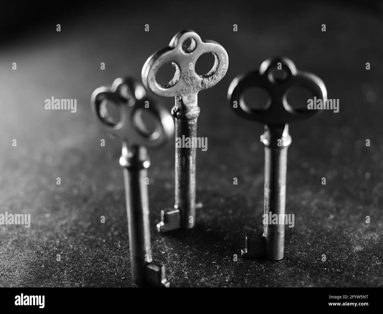 A black and white shot of old keys for a door on a black background ...