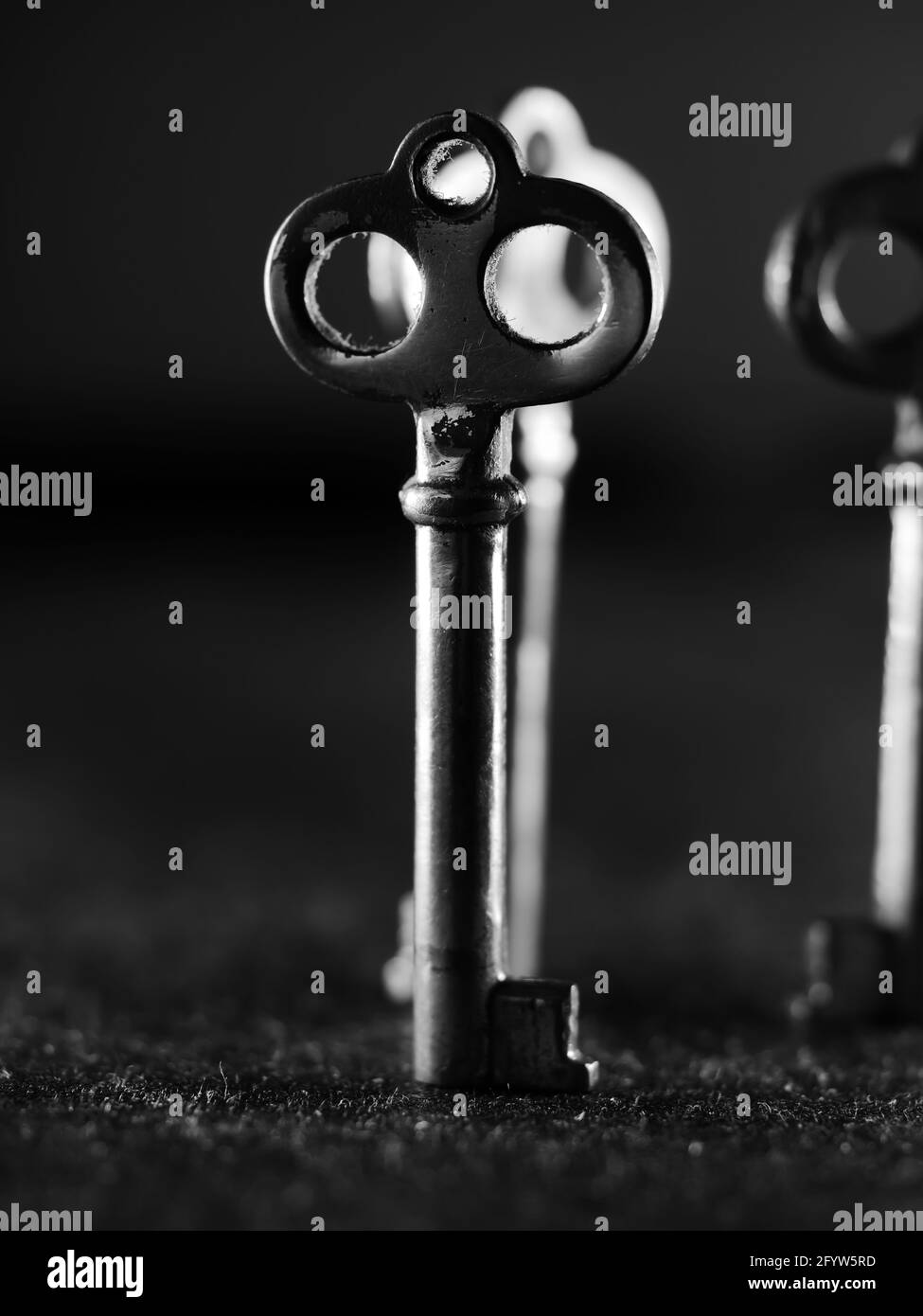 A black and white shot of old keys for a door on a black background ...