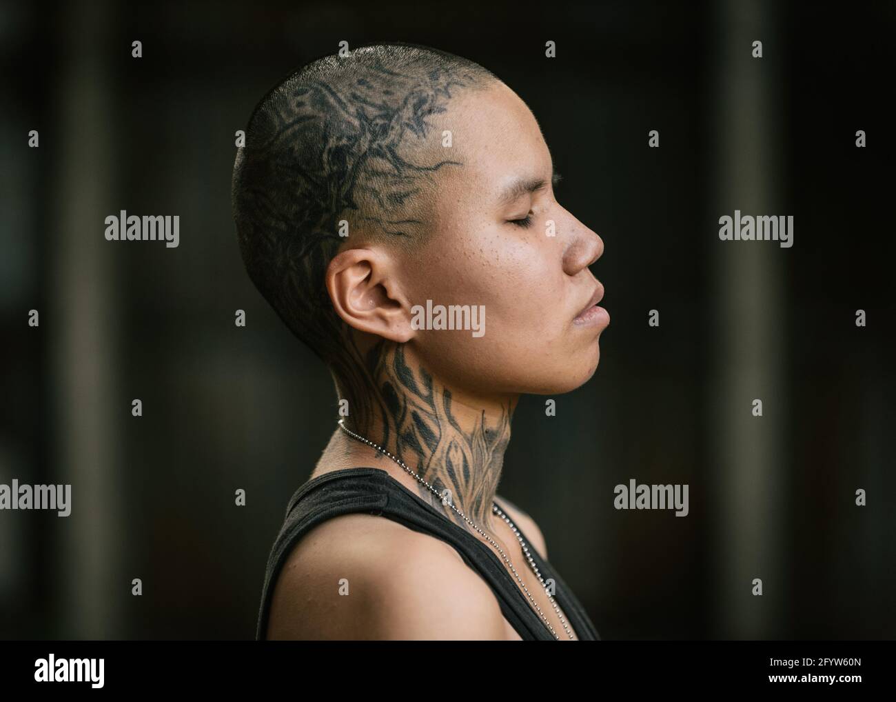 Portrait of a young skinhead Thai girl in profile view, heavily ...