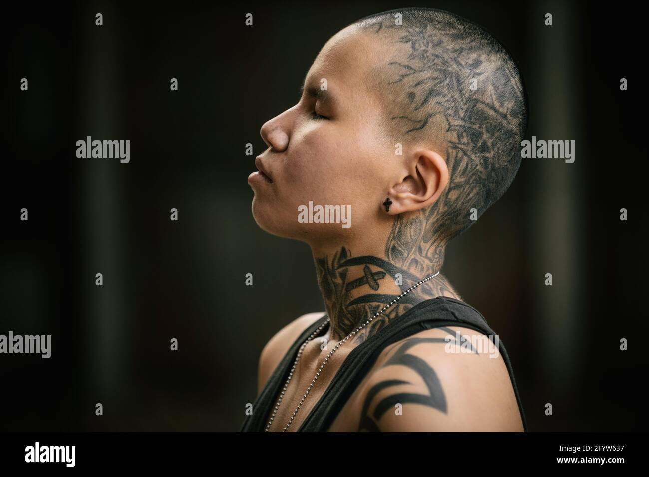Portrait of a young skinhead Thai girl in profile view, heavily ...