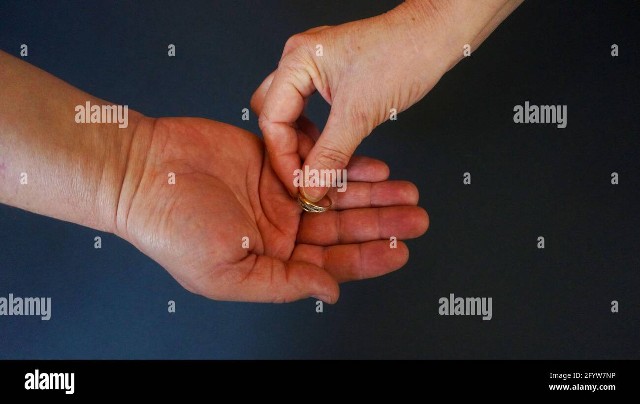 The hand of an old woman giving her wedding ring back to her husband ...
