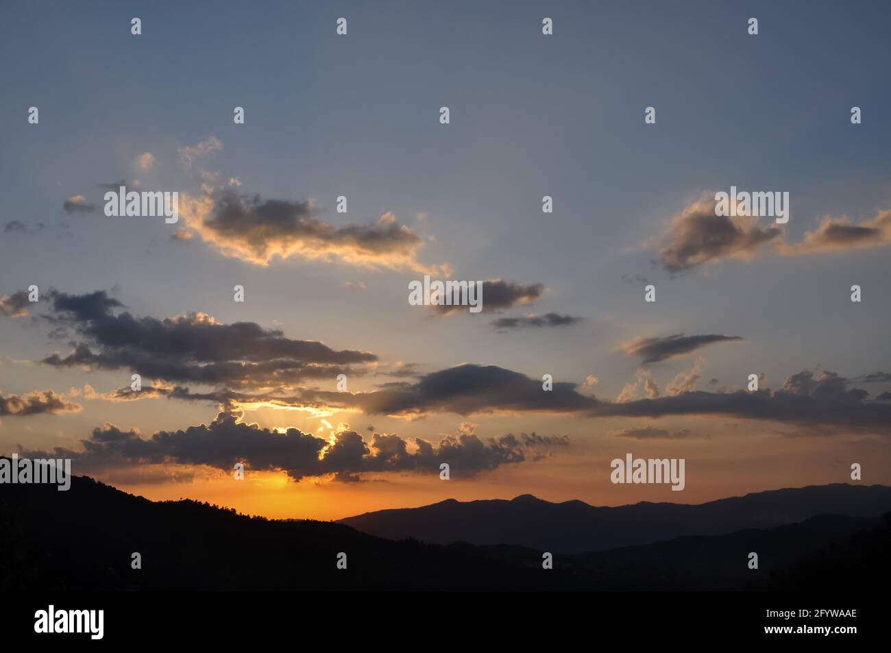 High resolution shot of sun behind clouds during sunset of hilly area ...
