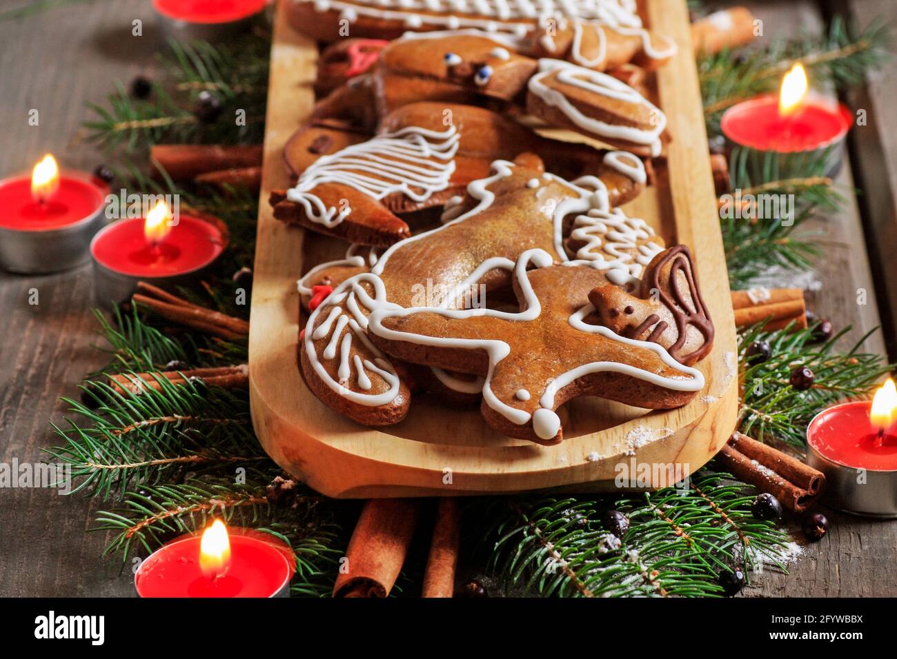 Gingerbread cookies on wooden tray among fir branches. Christmas sweets ...