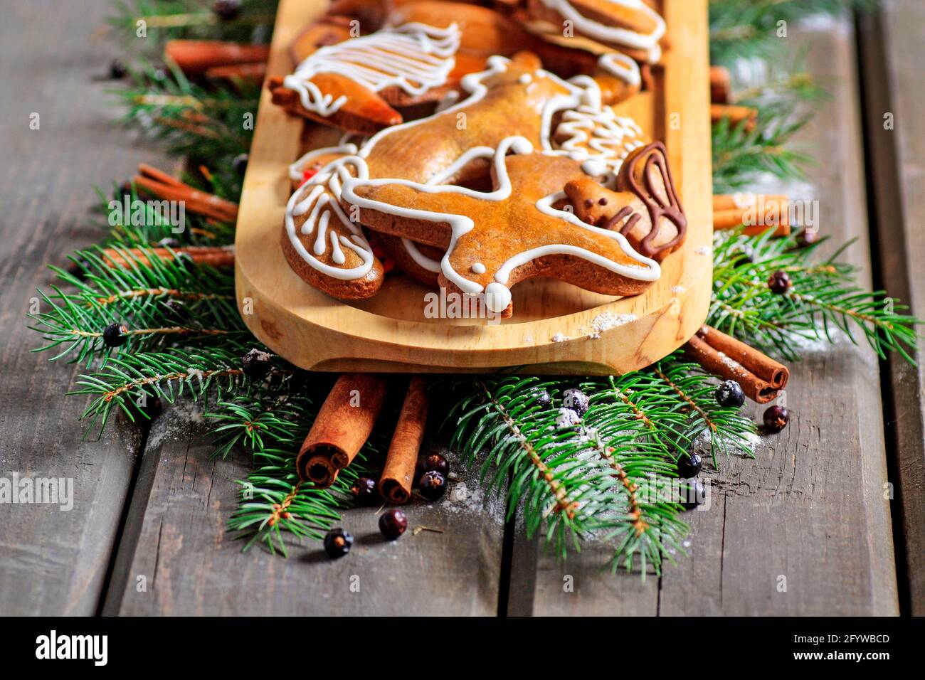 Gingerbread cookies on wooden tray among fir branches. Christmas sweets ...