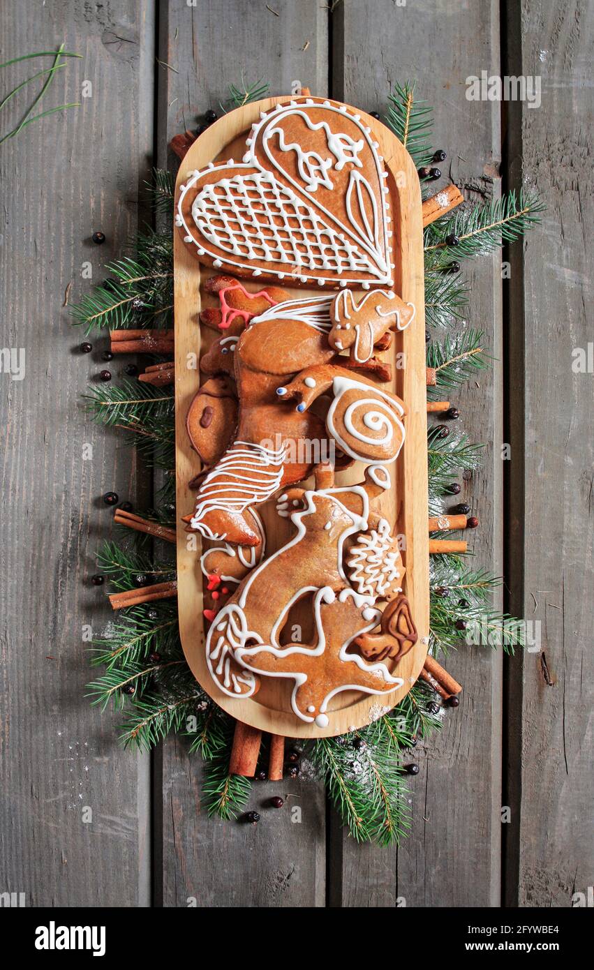 Gingerbread cookies on wooden tray among fir branches. Christmas sweets ...