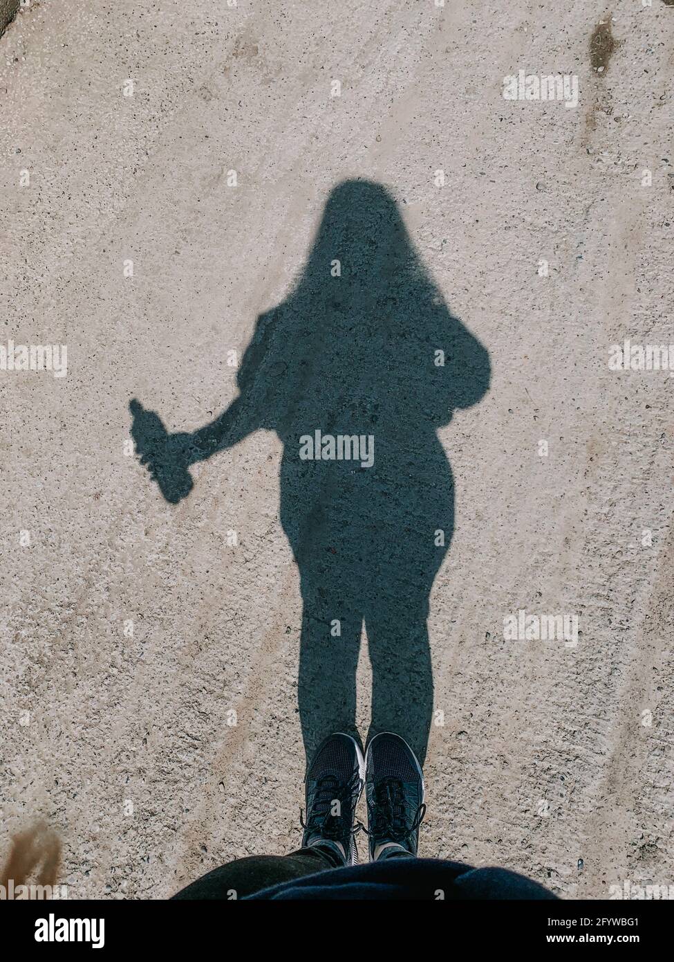 An overhead shot of a girl standing outdoors with her shadow on the ...