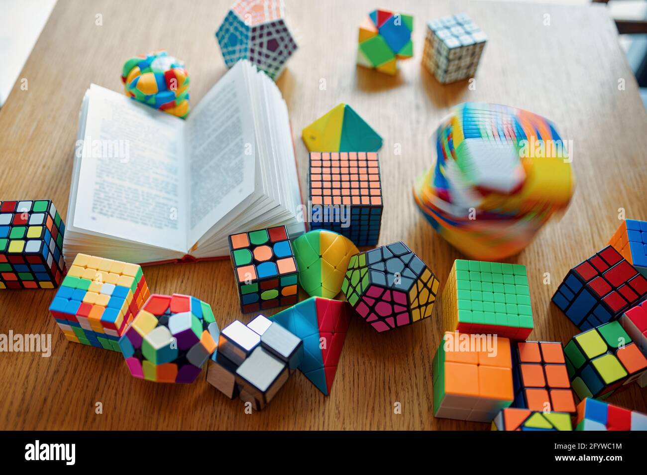Different puzzle cubes and opened book on table Stock Photo - Alamy