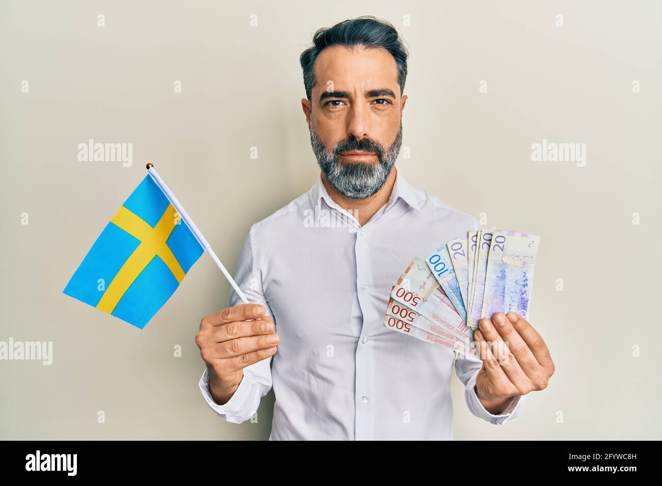 Middle age man with beard and grey hair holding sweden flag and krone ...