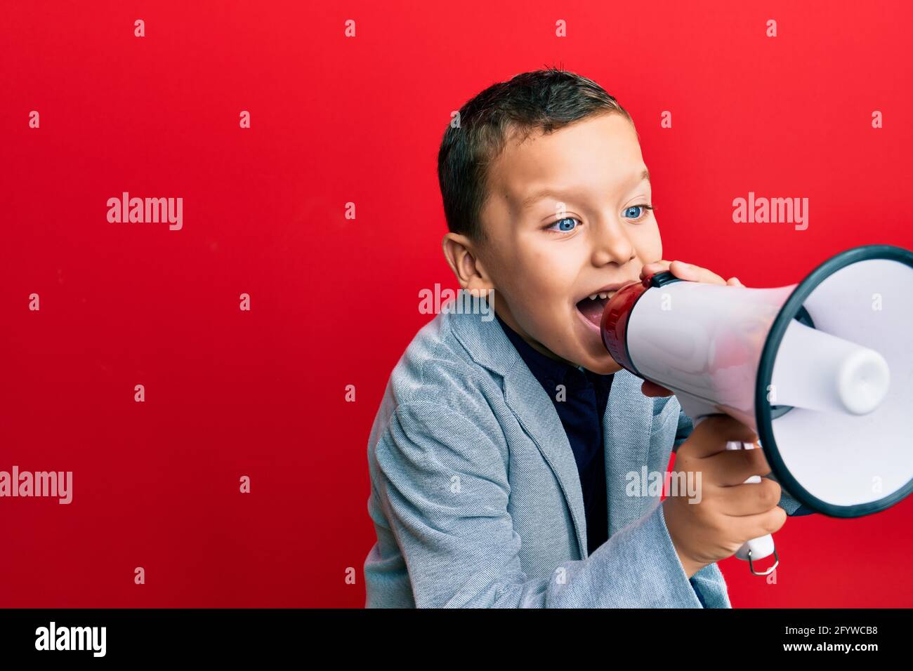 Adorable caucasian boy screaming using megaphone over isolated red ...