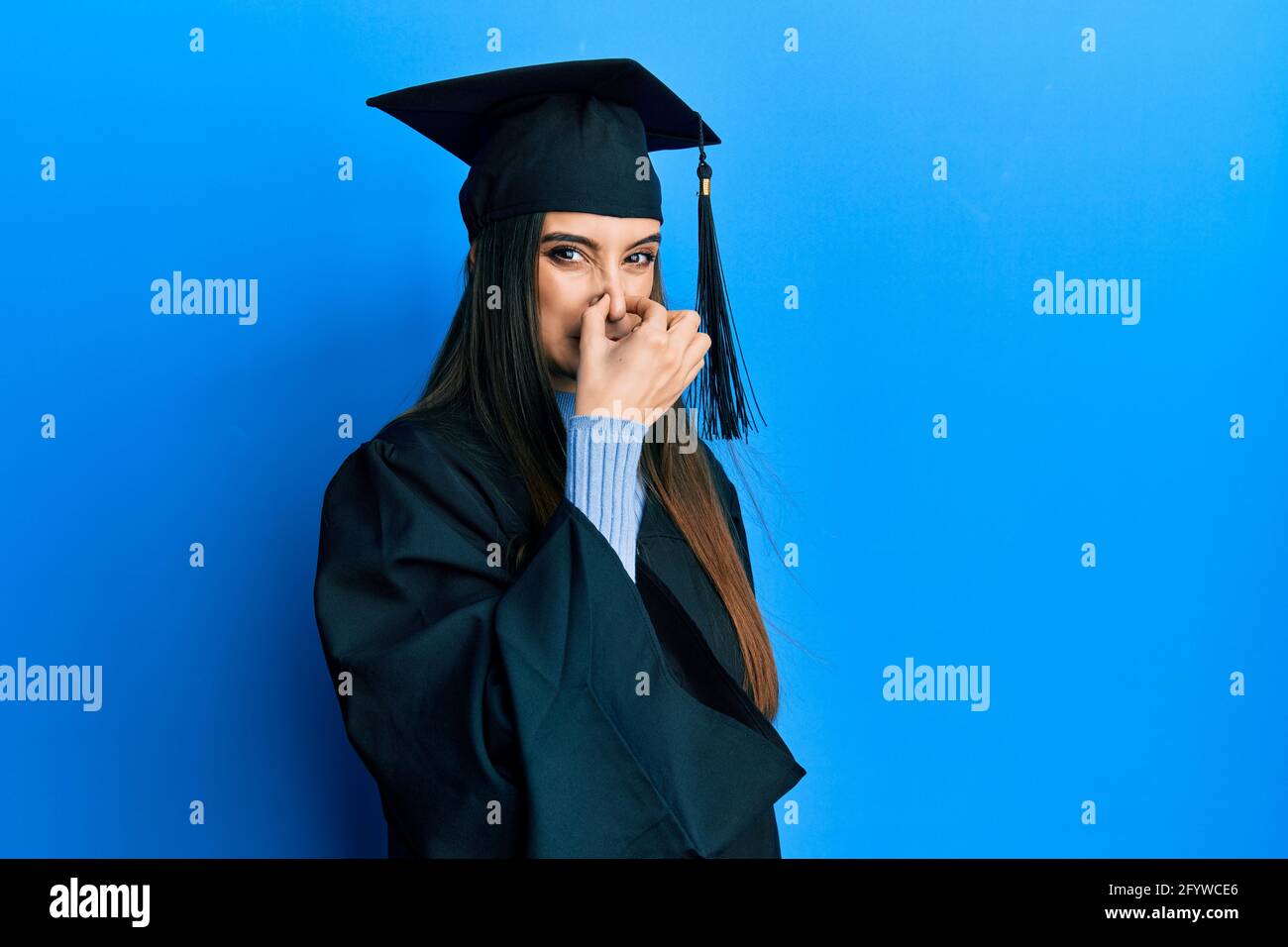Beautiful brunette young woman wearing graduation cap and ceremony robe ...