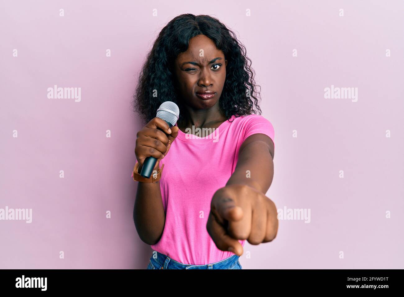Beautiful african young woman singing song using microphone pointing to ...