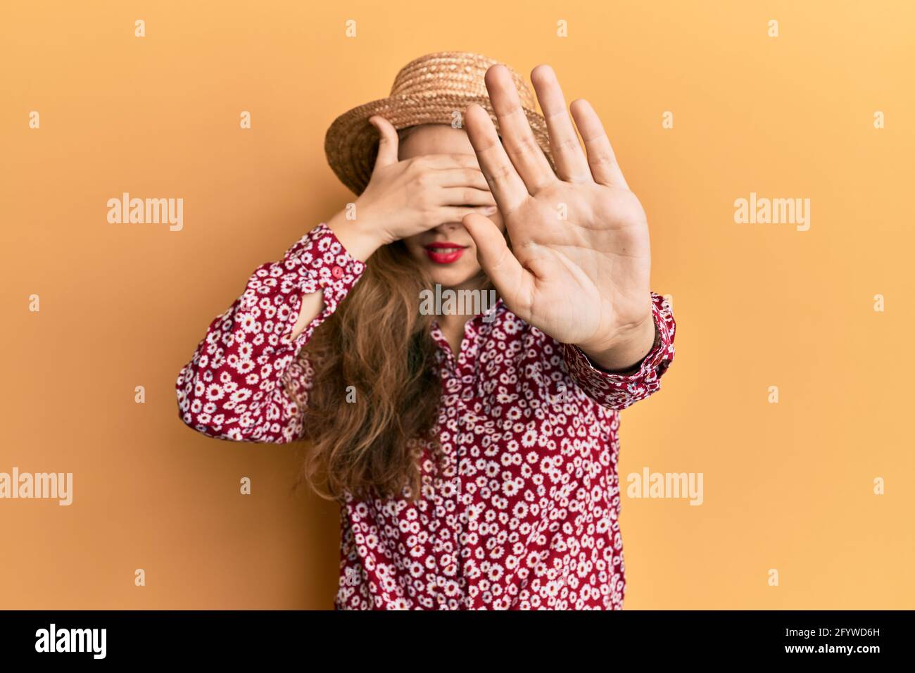 Beautiful blonde caucasian woman wearing summer hat covering eyes with ...