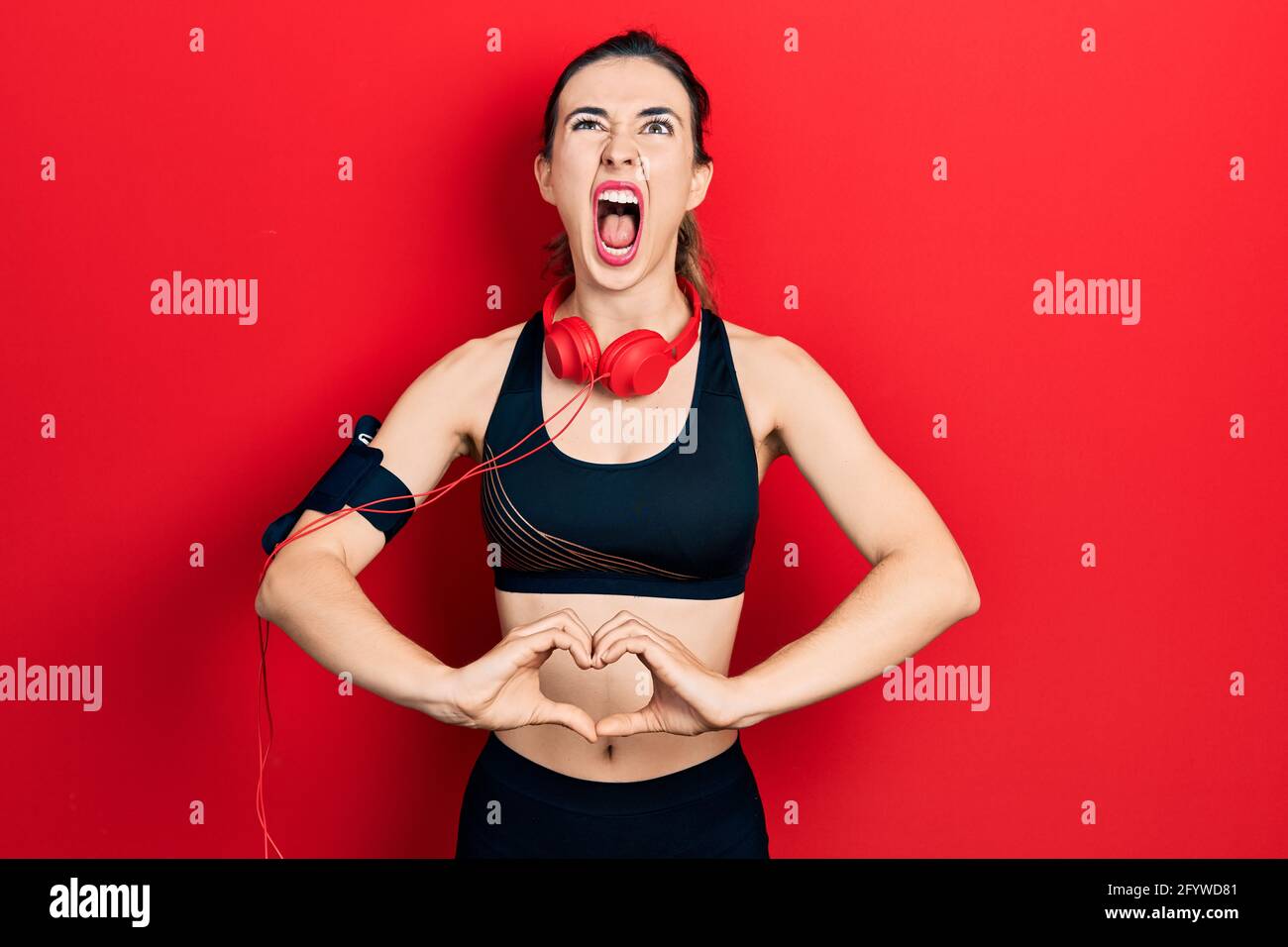 Young hispanic girl wearing gym clothes and using headphones doing ...