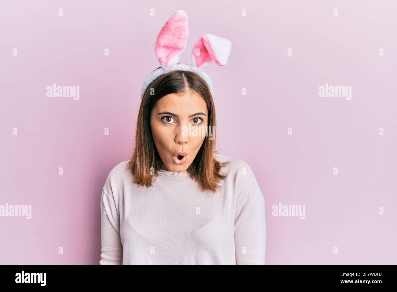 Young beautiful woman wearing cute easter bunny ears afraid and shocked ...