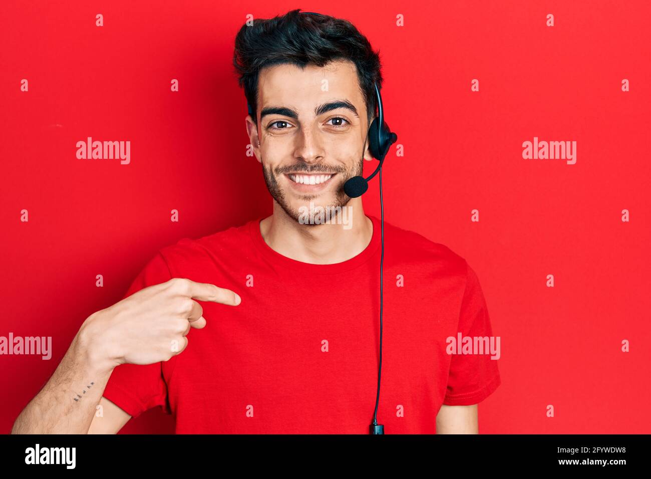 Young hispanic man wearing call center agent headset pointing finger to ...