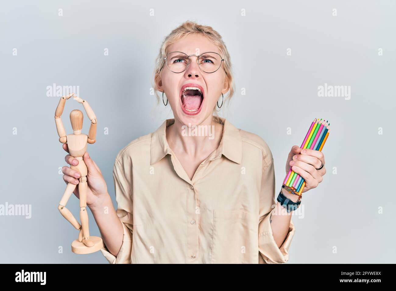 Beautiful caucasian woman with blond hair holding small wooden manikin ...