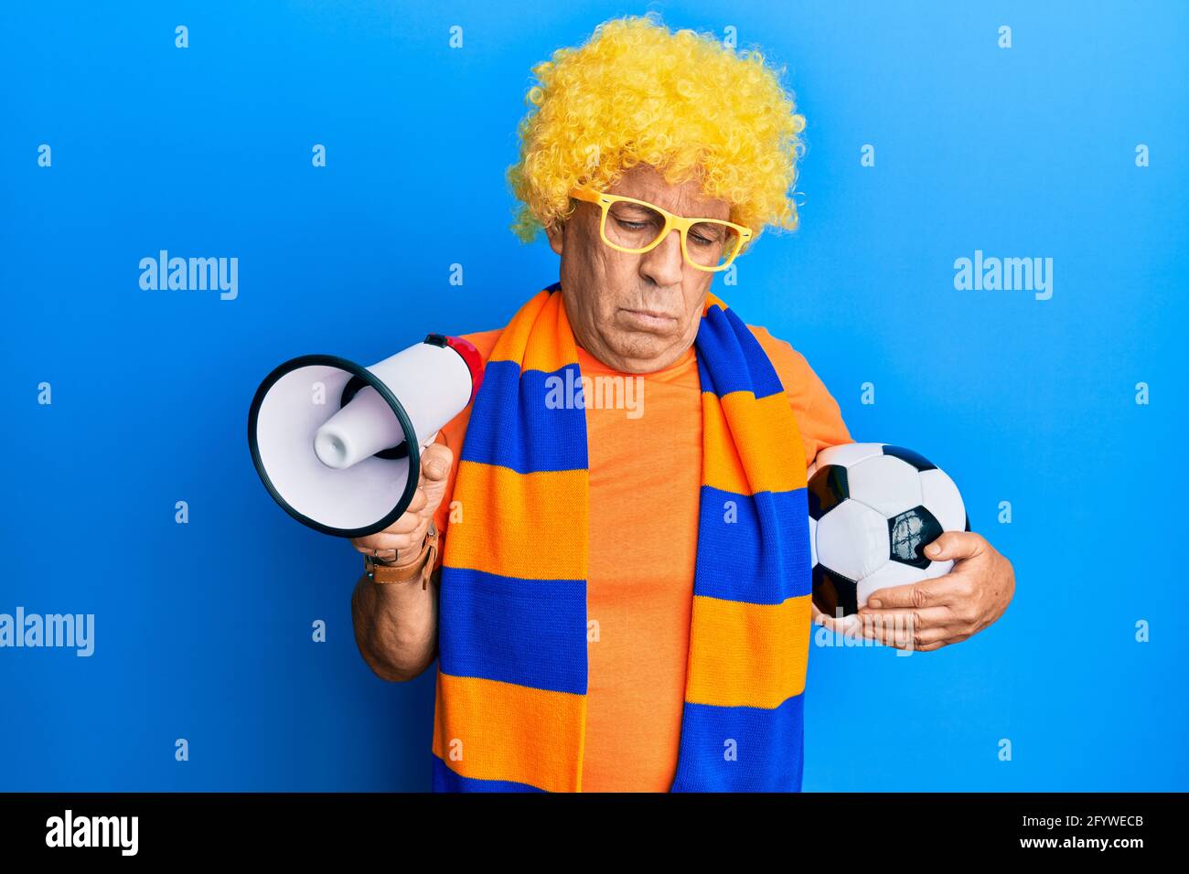 Senior hispanic man football hooligan cheering game holding ball and ...