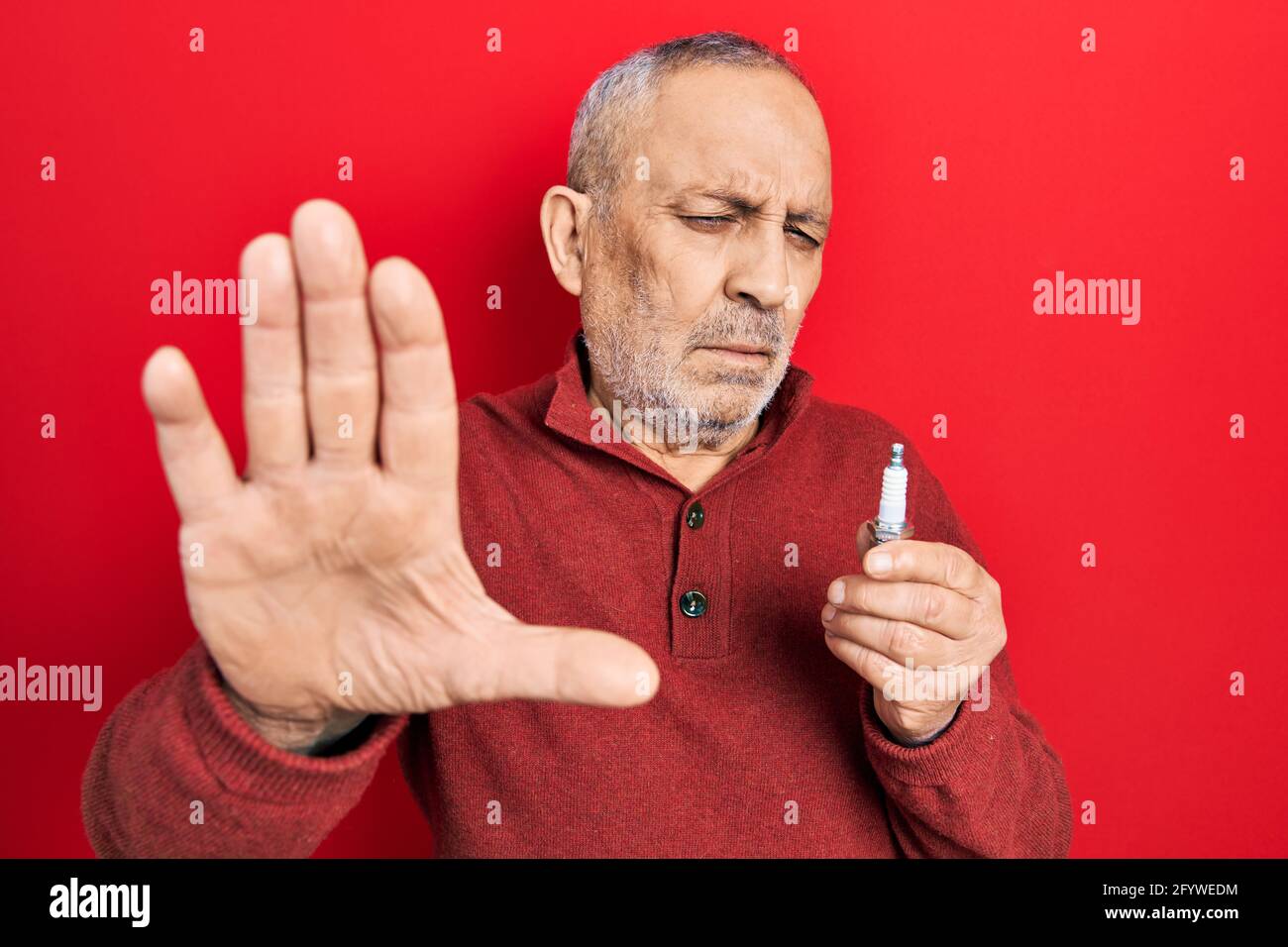 Handsome mature man holding spark plug with open hand doing stop sign ...