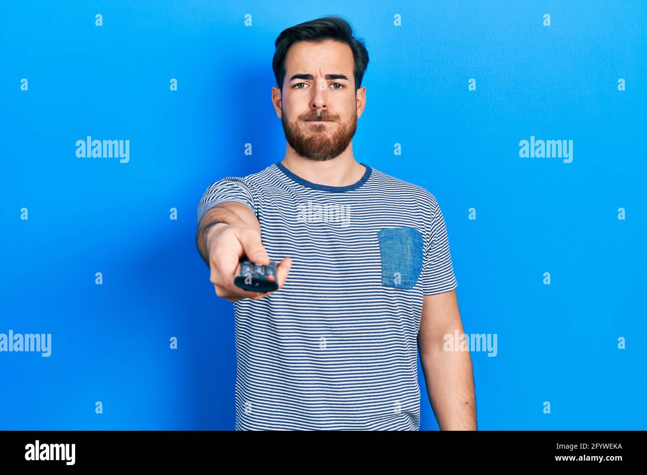 Handsome caucasian man with beard holding television remote control ...
