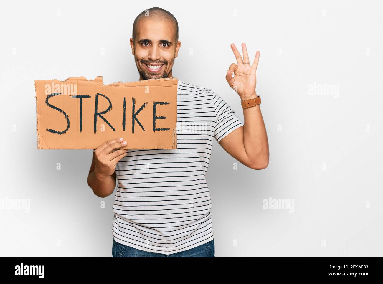 Hispanic adult man holding strike banner cardboard doing ok sign with ...